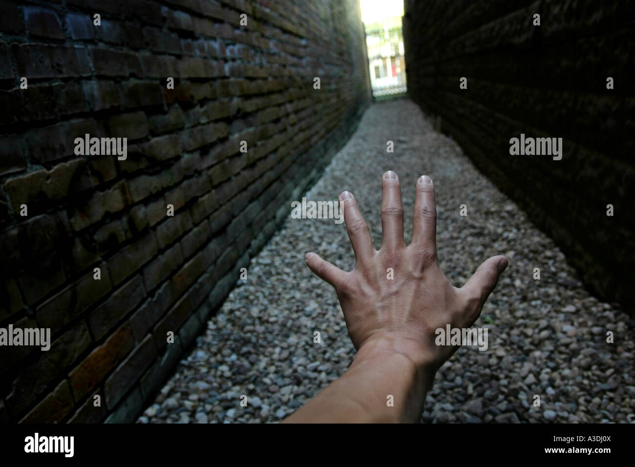 Hand reaching down narrow alley towards light Stock Photo - Alamy