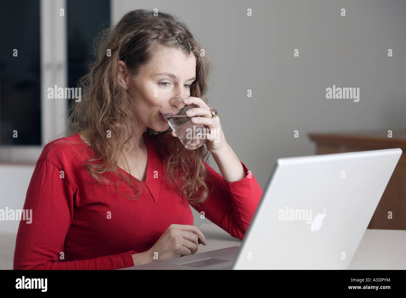 Young woman drinking water while working at a PC Stock Photo - Alamy