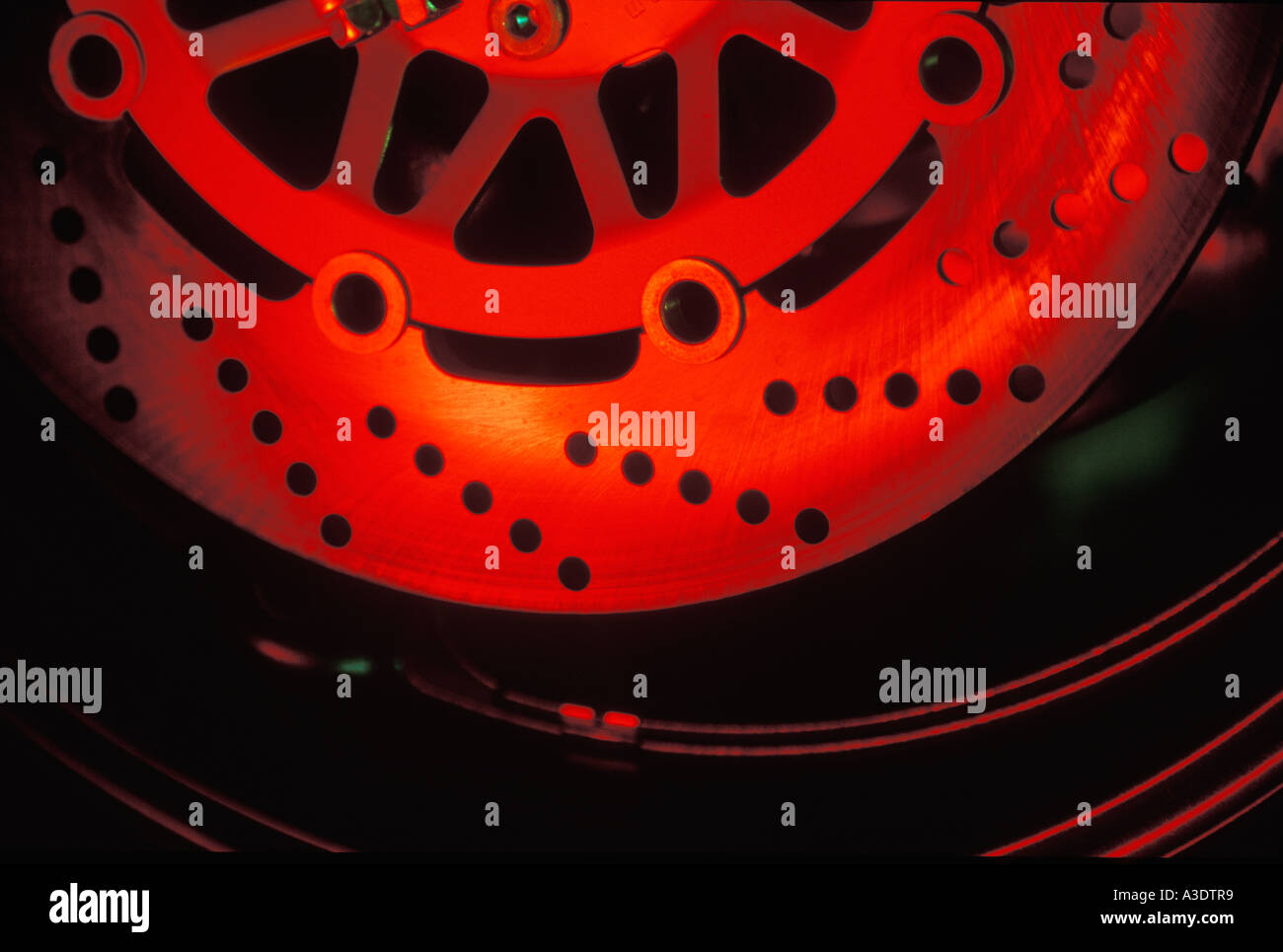 Part of the disc-brake on a wheel of a Harley Davidson motorcycle lit ...