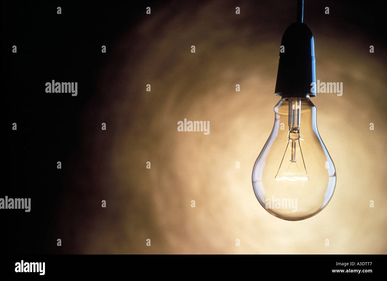 Clear-glass lightbulb hanging in a black electrical socket with glowing ...