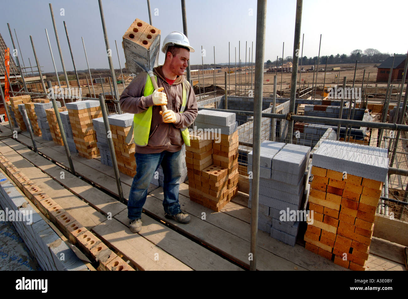 A strong fit young brickie shoulders a hod of bricks on a building site ...