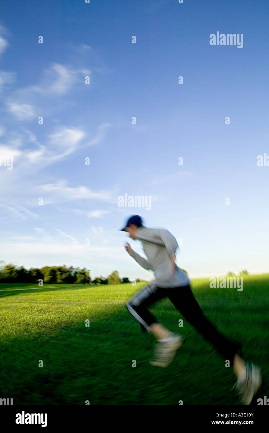 Energetic teenage boy running In springtime green fields Stock Photo ...
