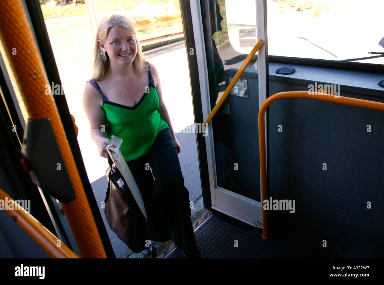Young woman boarding bus in city street, smiling at camera Stock Photo ...