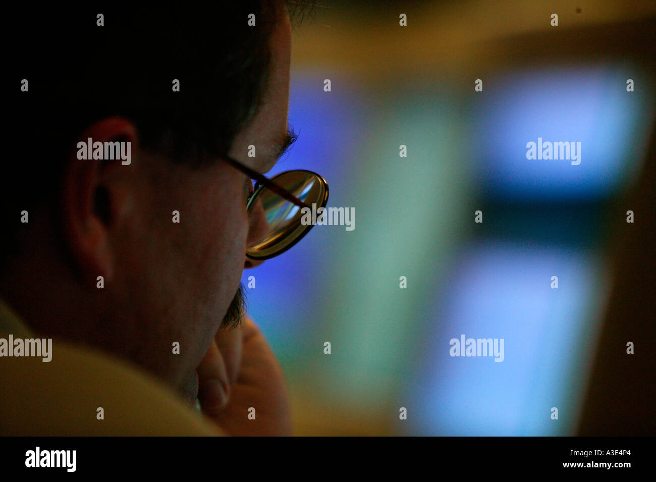 Computer room, man looking at screen refracting through his glasses ...