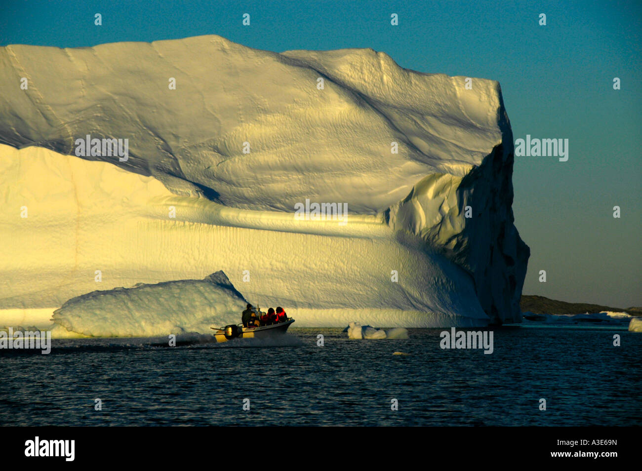 Small motor boat at the edge of a huge iceberg Sermilik Fjord ...