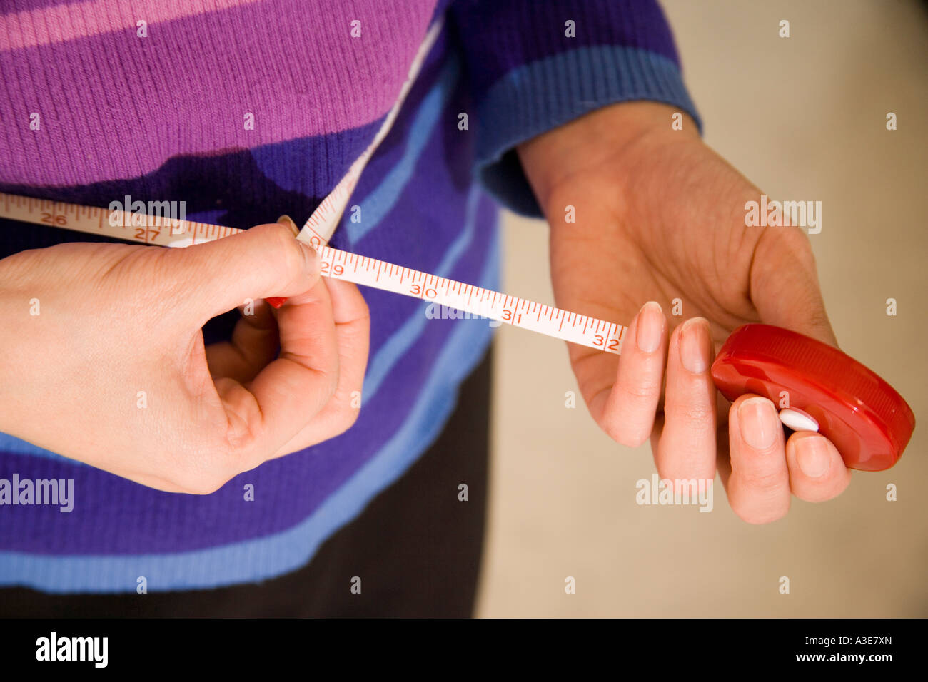 Woman measures her waist using a tape measure Stock Photo - Alamy