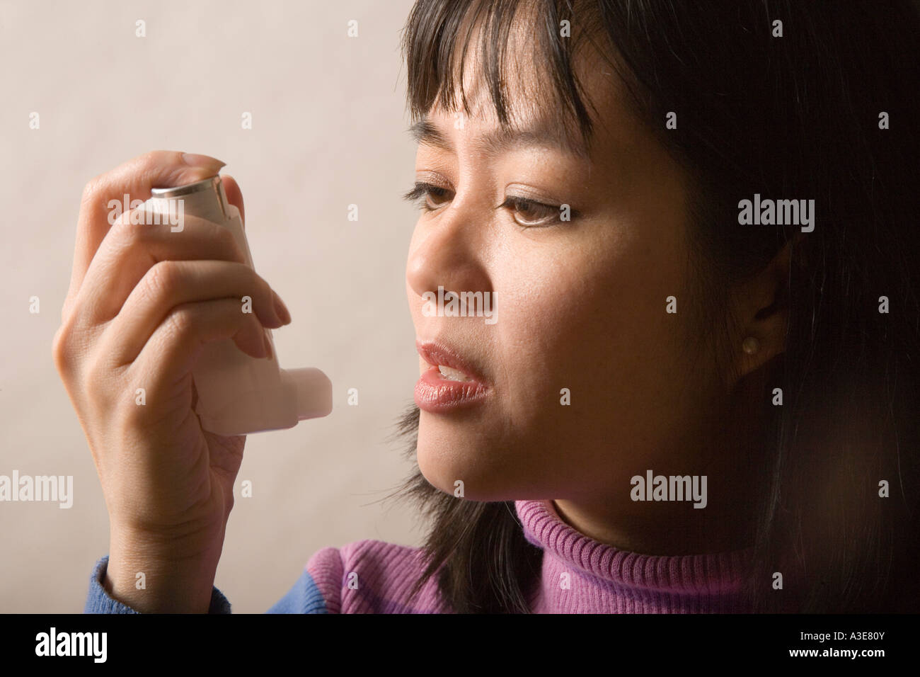Woman using a bronchial dilator for asthma relief. Also known as an ...