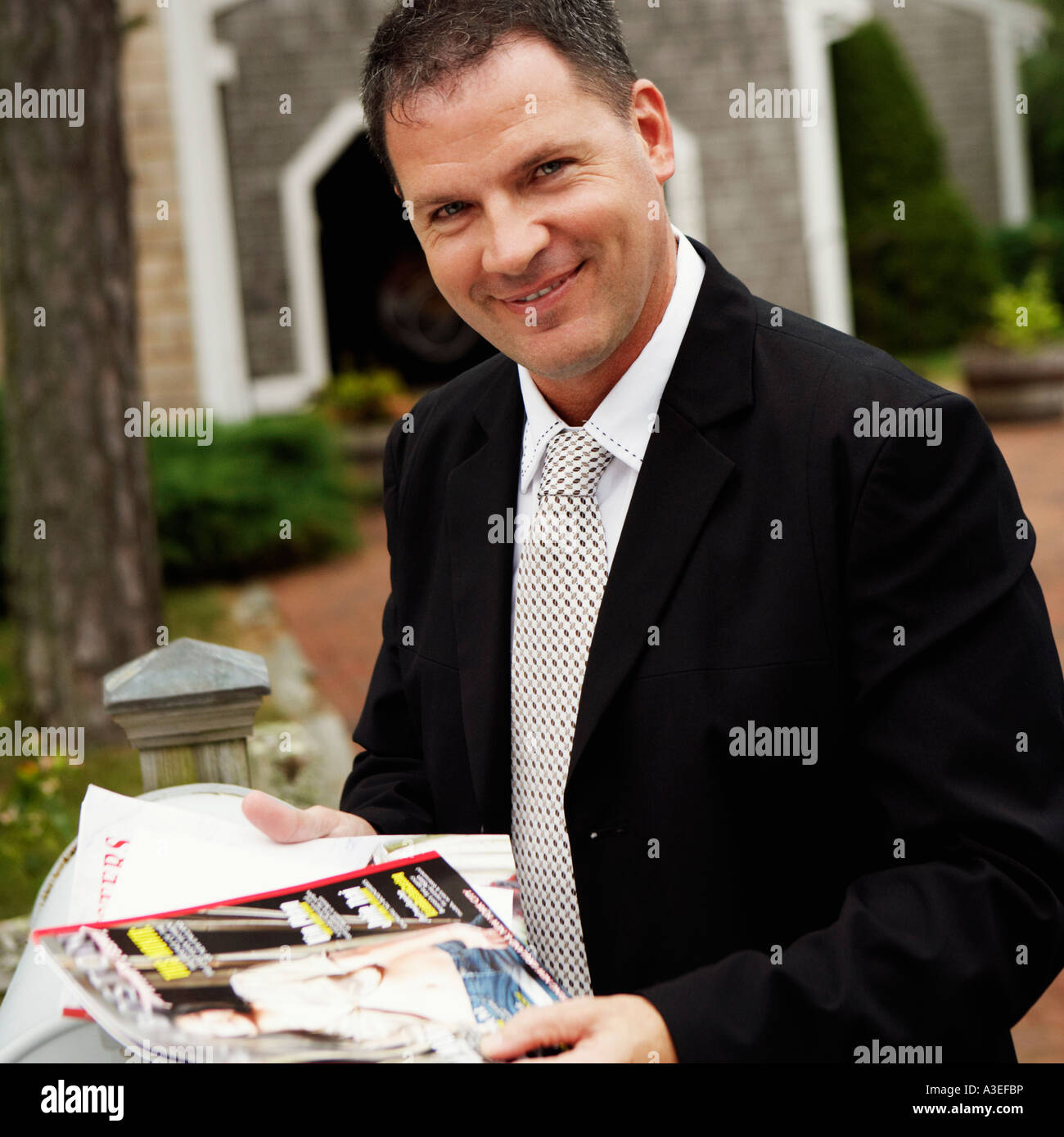 Portrait of a businessman holding magazines and smiling Stock Photo - Alamy
