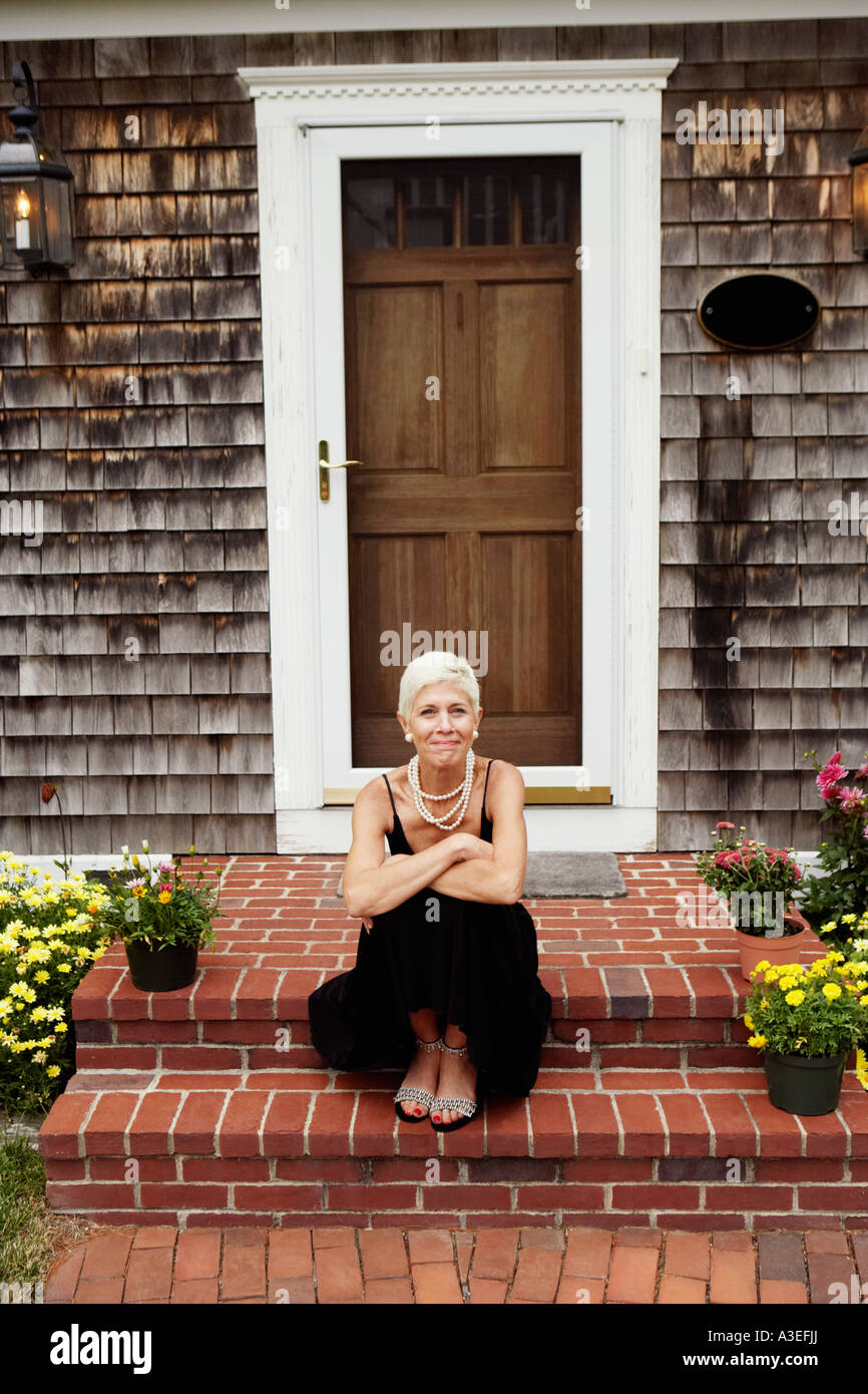 Portrait of a senior woman sitting at the front stoop of house Stock ...