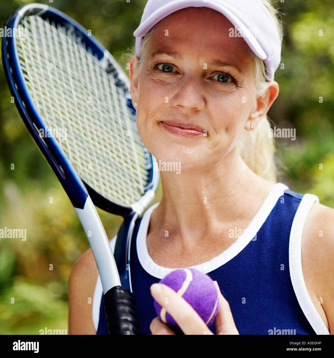 Portrait of a mature woman holding a tennis racket and a tennis ball ...