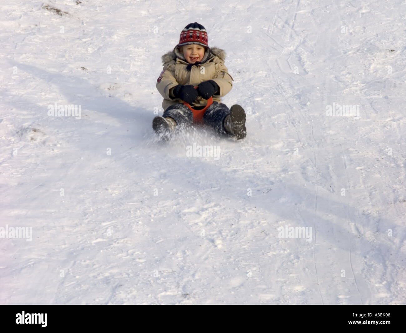 In Winter Kids play ski-sliding from slope down on ice Stock Photo - Alamy