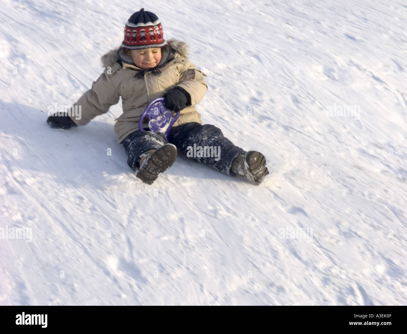 In Winter Kids play ski-sliding from slope down on ice Stock Photo - Alamy