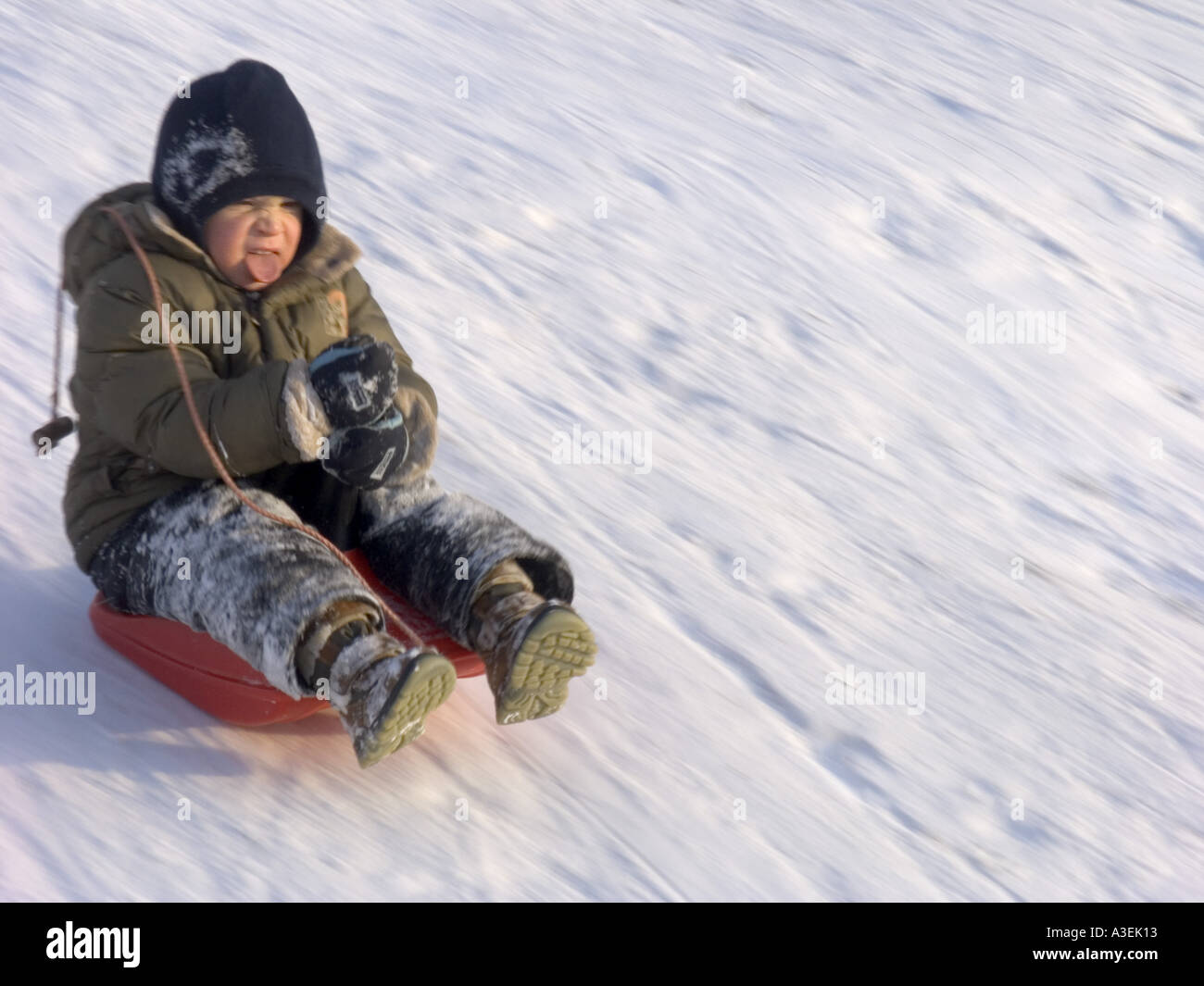 In Winter Kids play ski-sliding from slope down on ice Stock Photo - Alamy