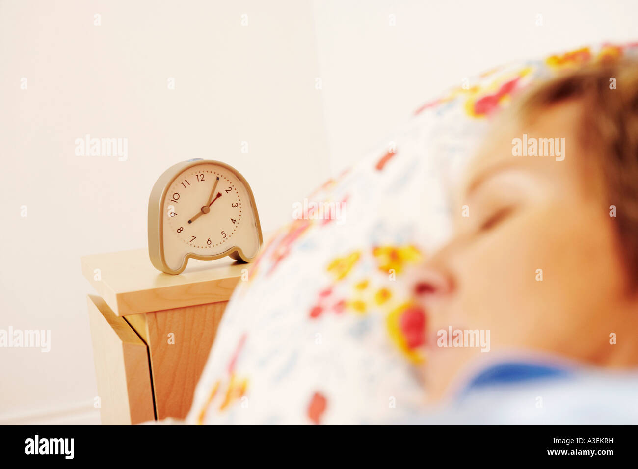 An alarm clock beside a mature woman sleeping on the bed Stock Photo ...