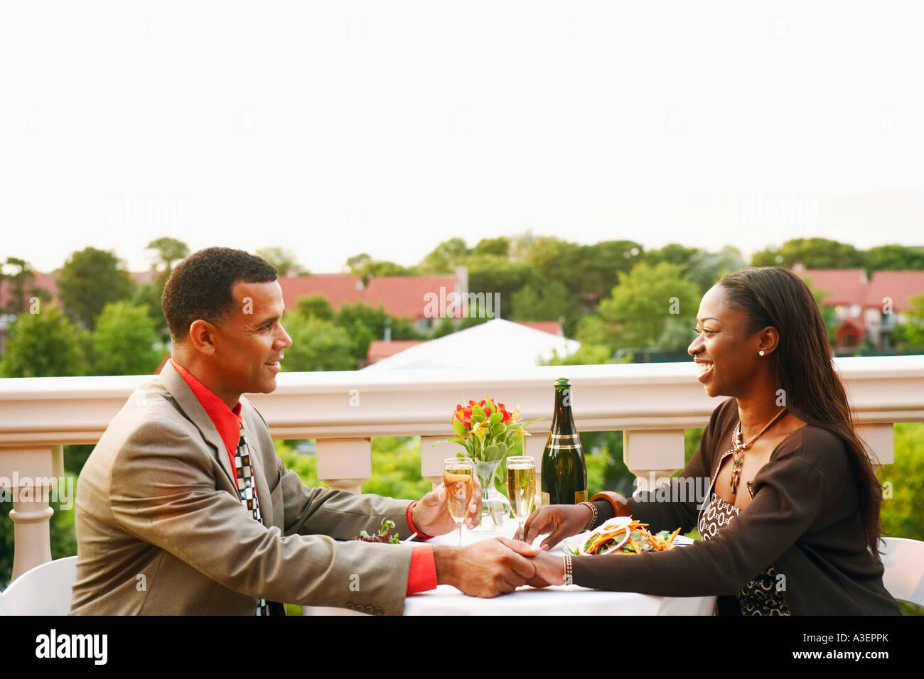 Side profile of a couple sitting at a table and smiling Stock Photo - Alamy