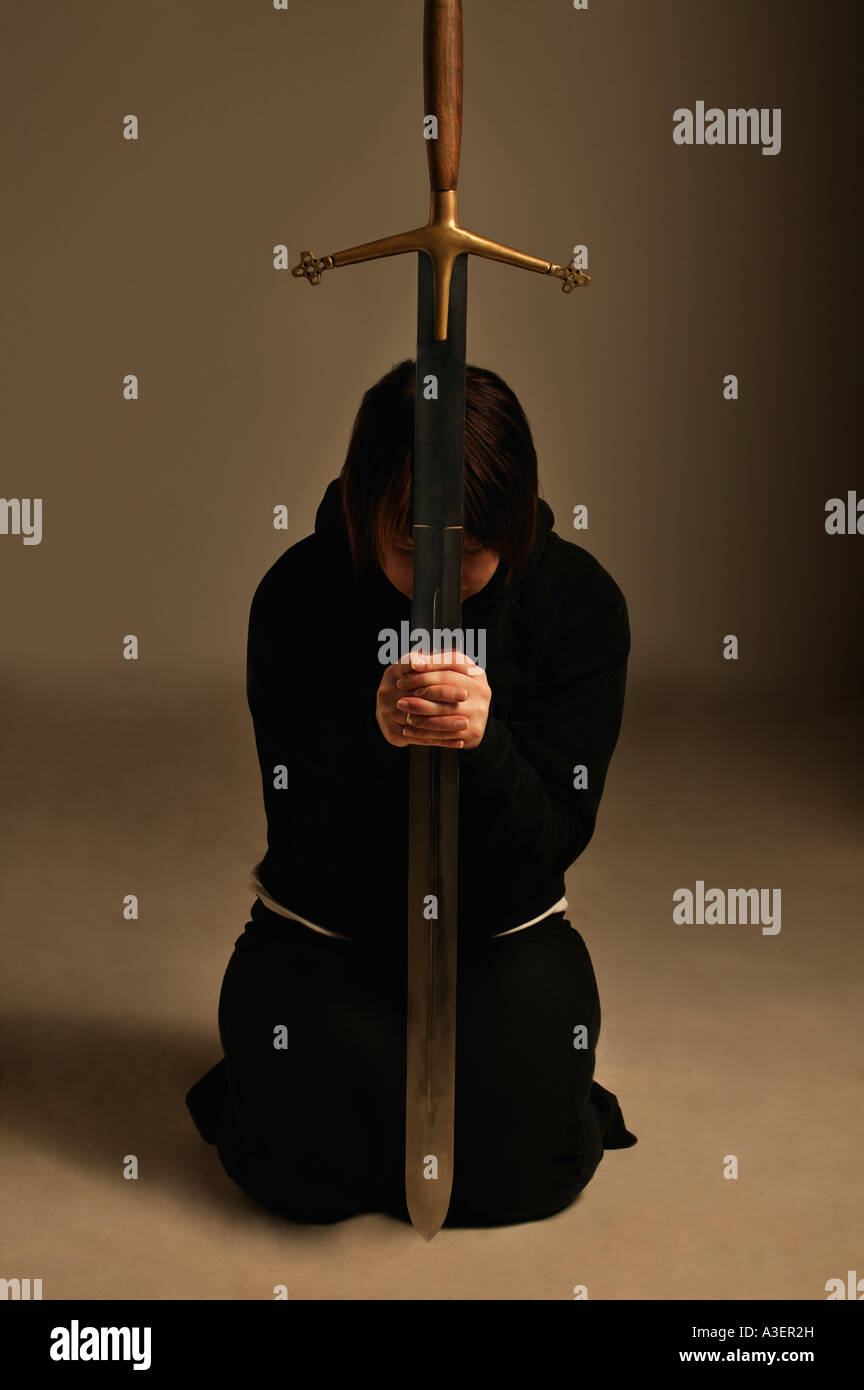 Person kneeling with a sword Stock Photo - Alamy