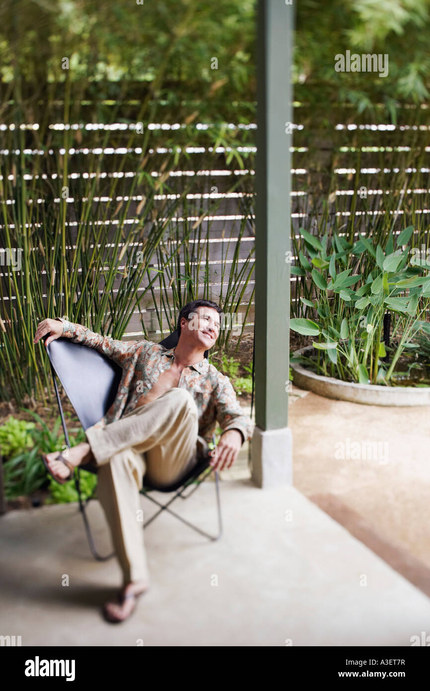 Mature man sitting on a chair on a porch Stock Photo - Alamy