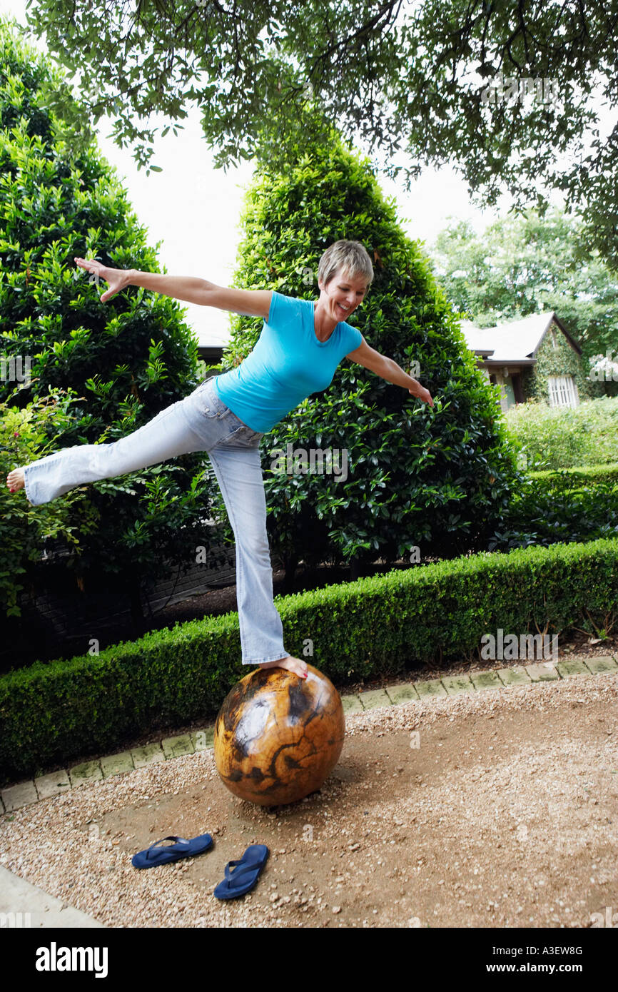 Mature woman standing on one leg on a rock Stock Photo - Alamy