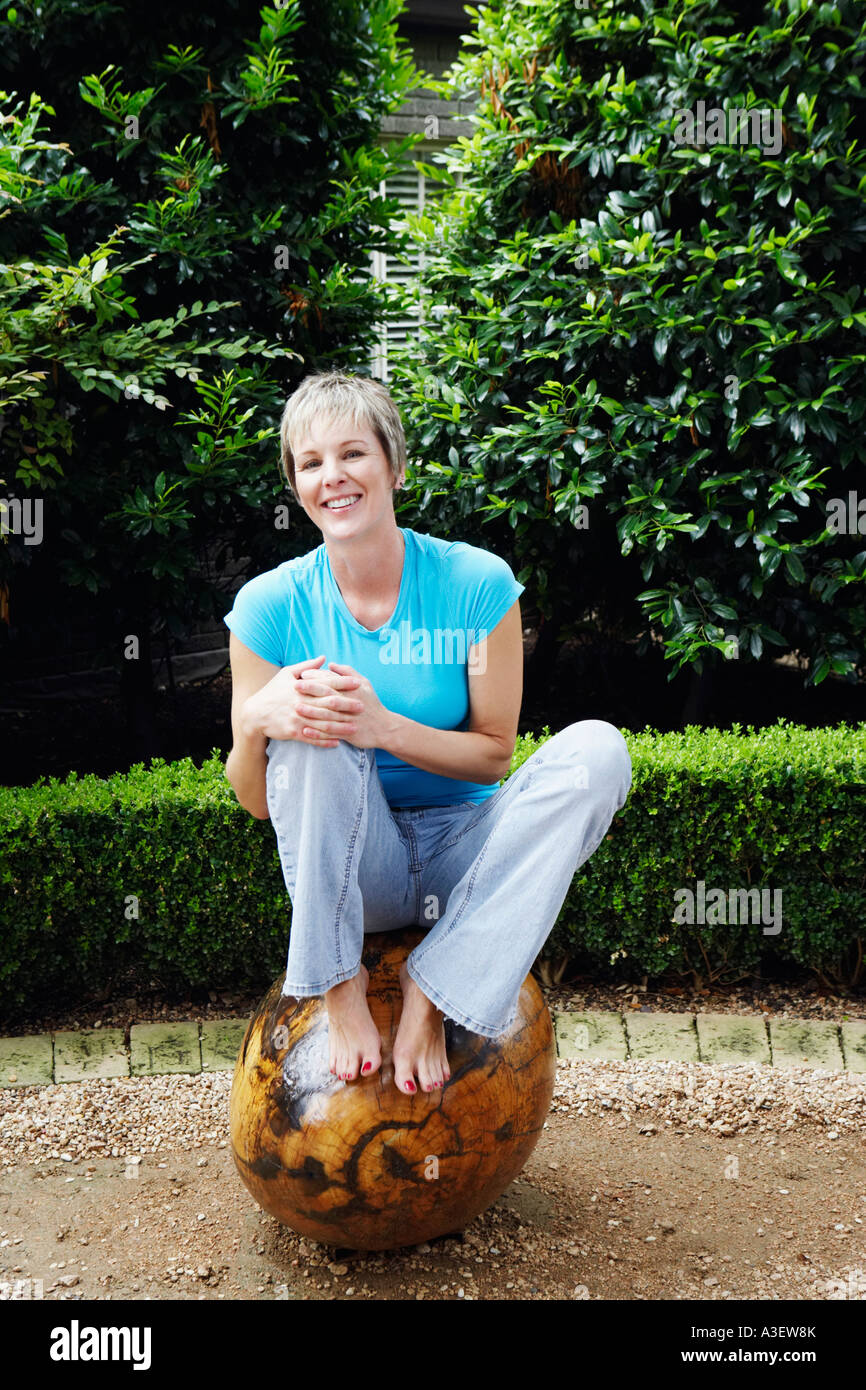 Mature woman sitting on a tree Stock Photo - Alamy