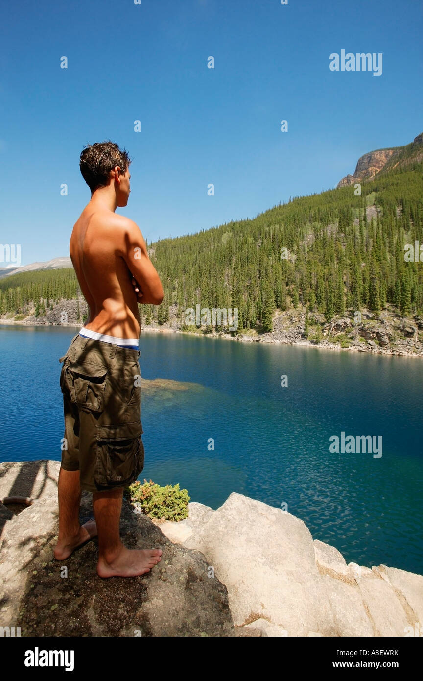 Young man looking out from cliff Stock Photo - Alamy