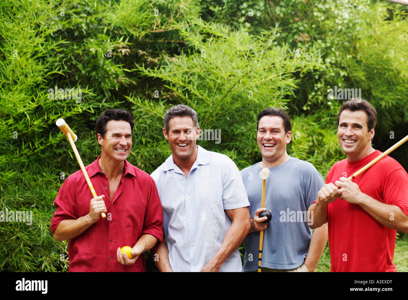 Mid adult man with three mature men holding croquet mallets and smiling ...