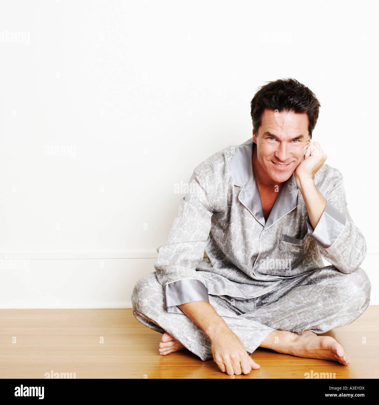 Portrait of a mature man sitting cross-legged on the floor and smiling ...