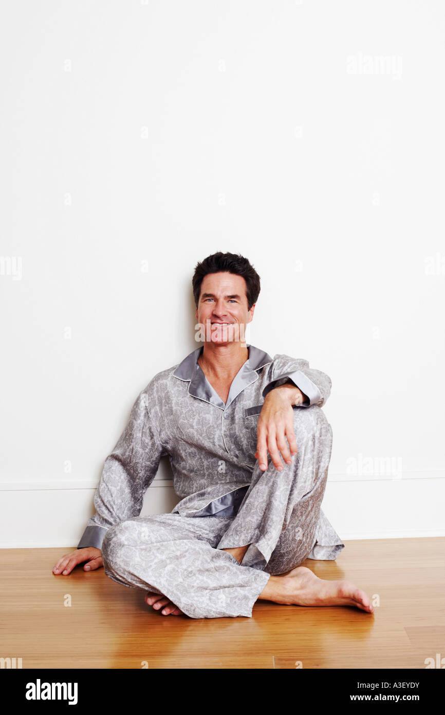 Portrait of a mature man sitting on the floor with his hand on his knee ...