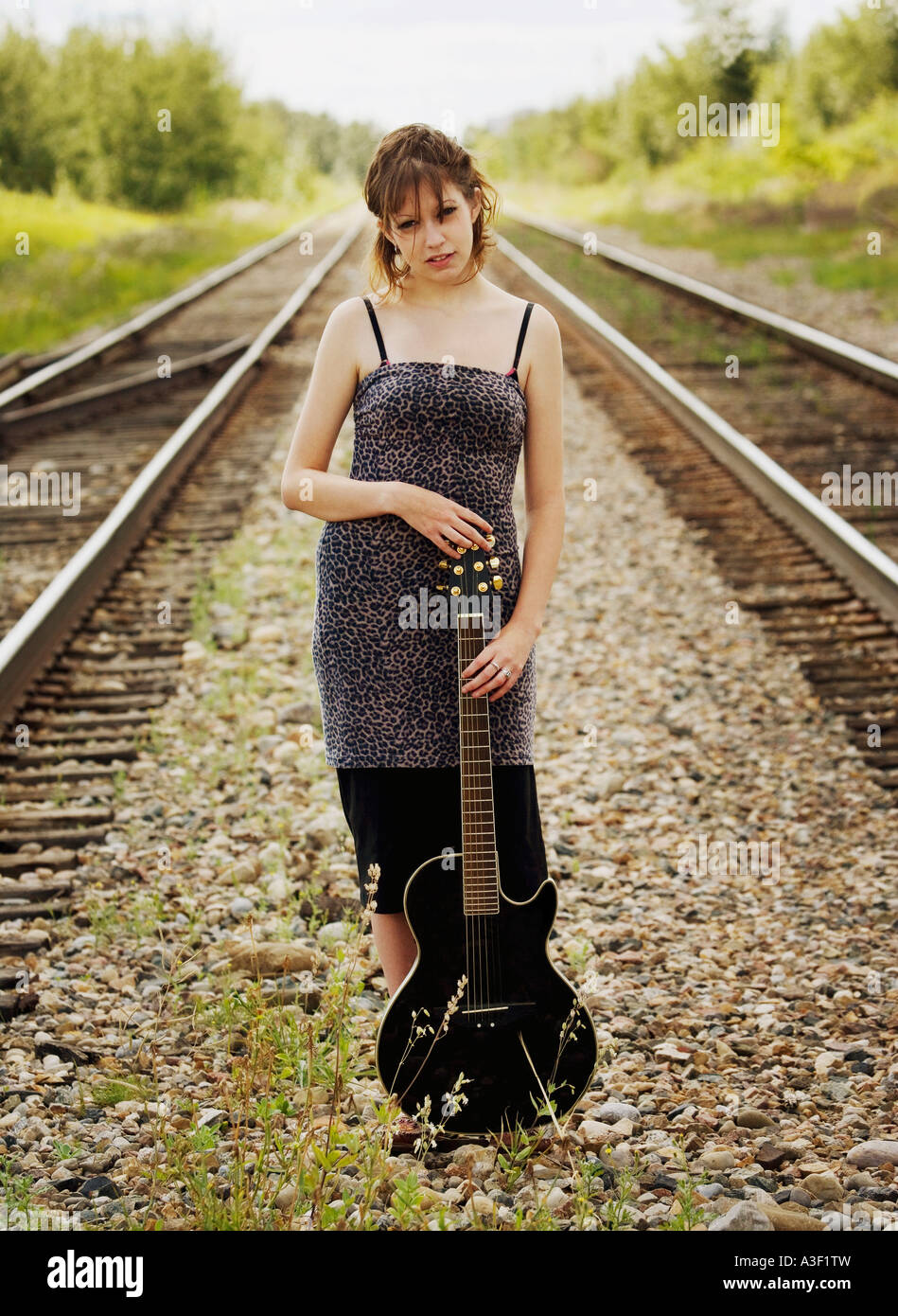 Young woman holding acoustic guitar on train tracks Stock Photo - Alamy