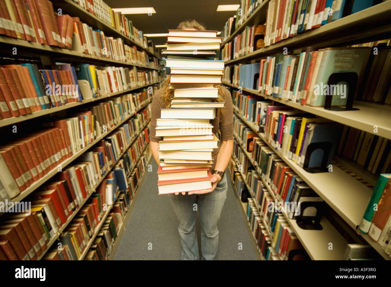 Student with large stack of books Stock Photo - Alamy