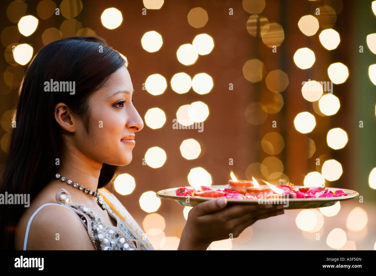 Side profile of a young woman holding oil lamps and Rose petals in a ...