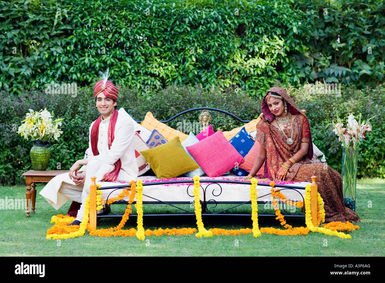 Portrait of a newlywed couple in traditional wedding dress sitting on ...