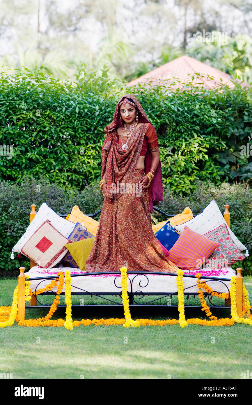Portrait of a bride in a traditional wedding dress standing on the bed ...