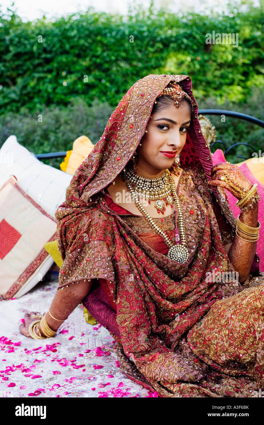 Portrait of a bride in a traditional wedding dress sitting on the bed ...