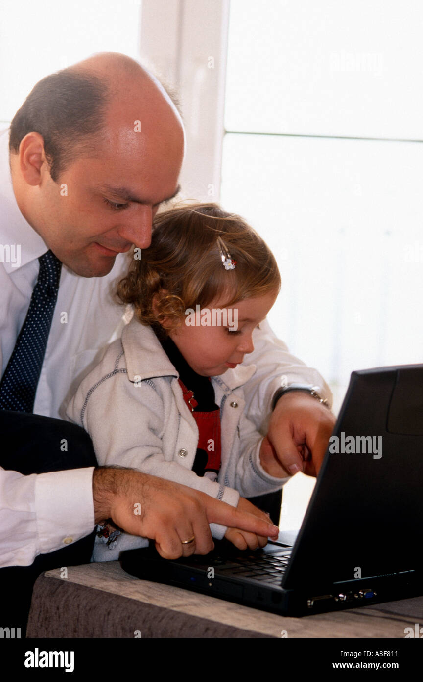 Father teaching daughter how to use laptop indoors Stock Photo - Alamy