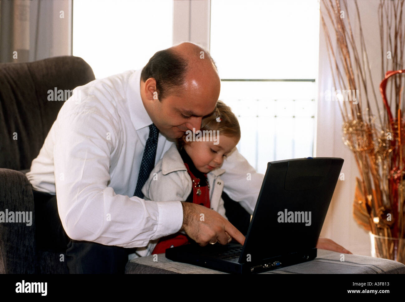 Father teaching daughter how to use laptop indoors Stock Photo - Alamy