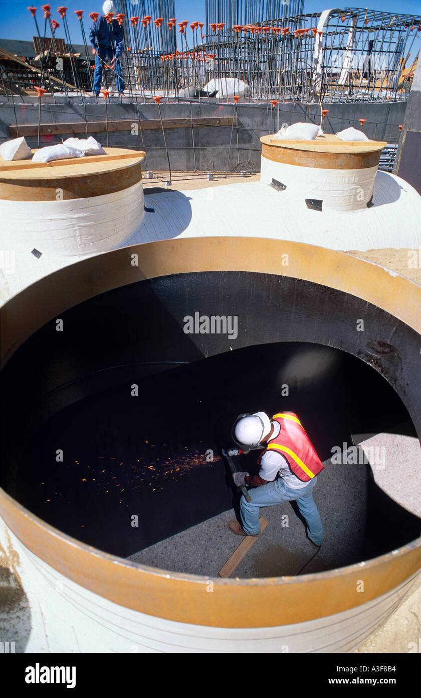 Workers inspect and work on industrial sized cooling pipes for power ...