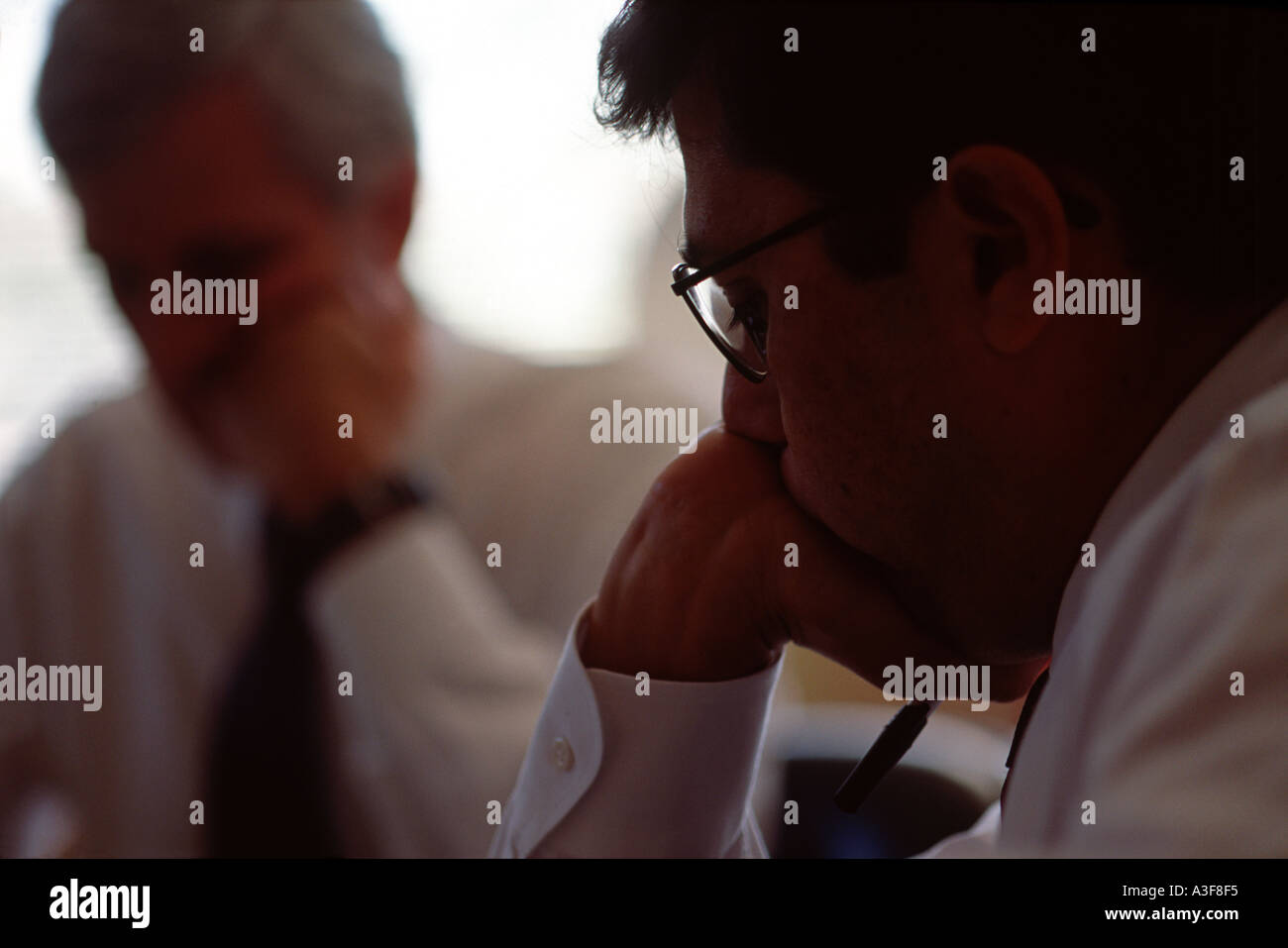 Two executive men thinking with hands on chin Stock Photo - Alamy