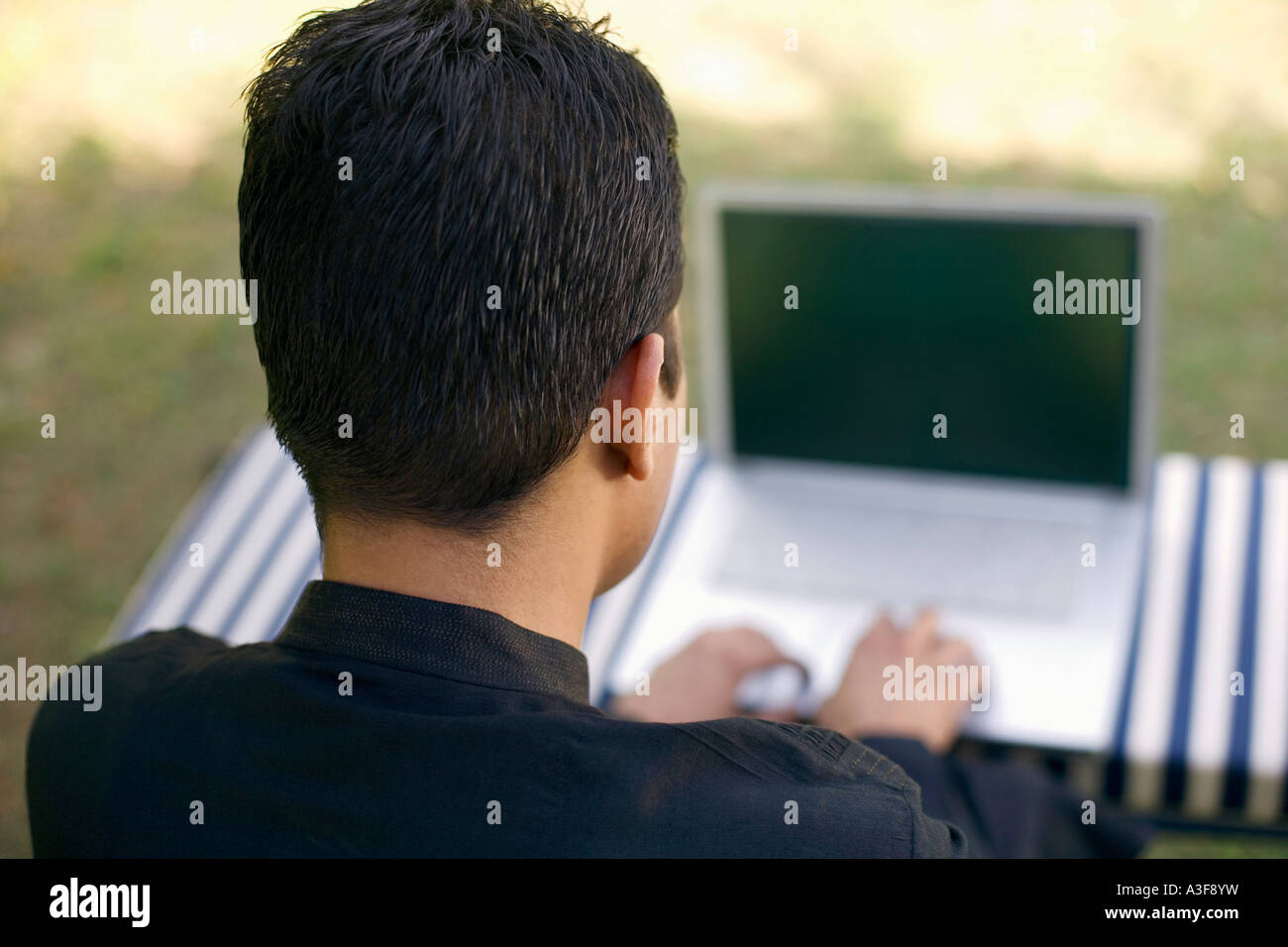 Rear view of a mid adult man using a laptop Stock Photo - Alamy