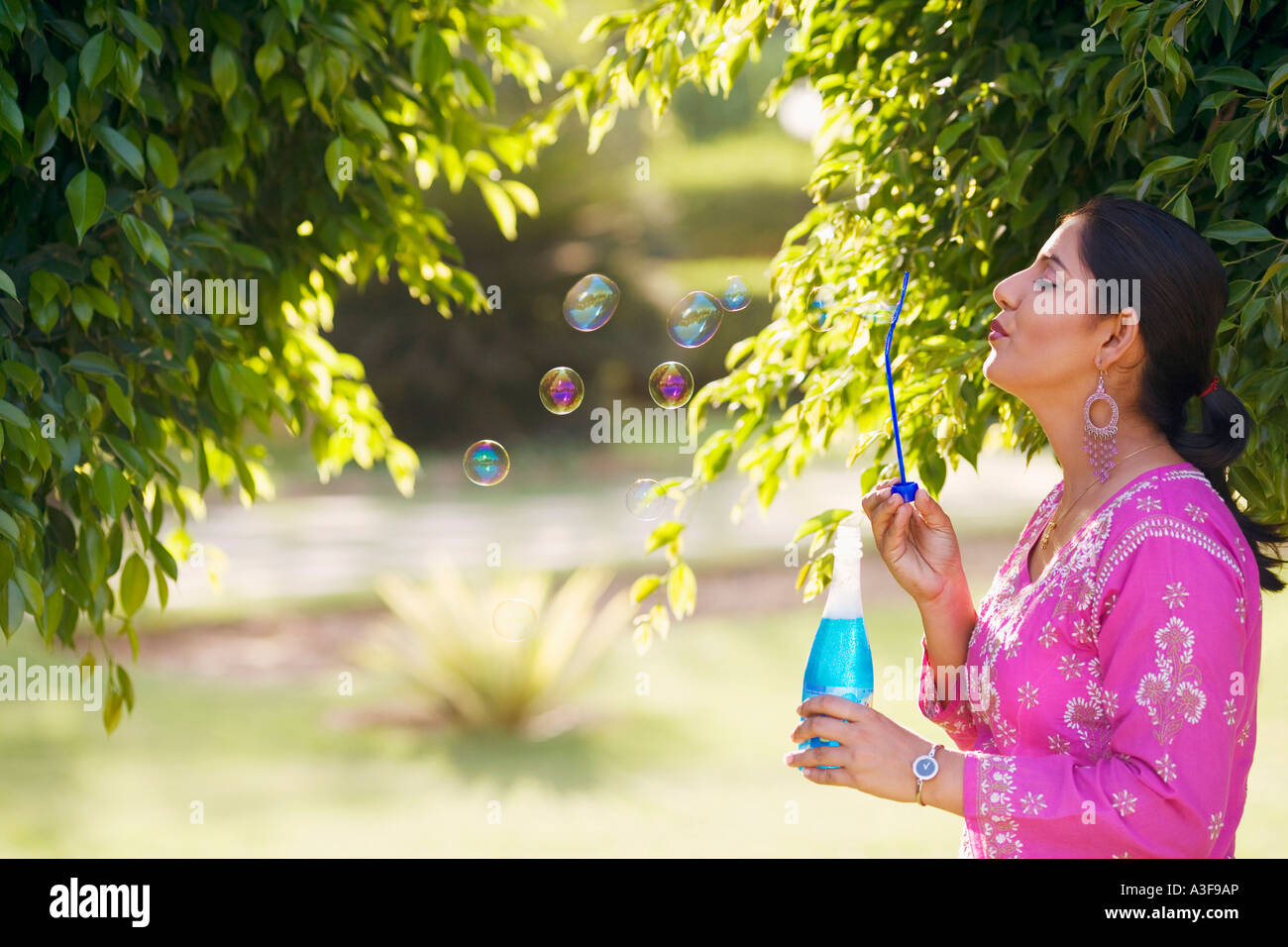 Side profile of a young woman blowing bubbles Stock Photo - Alamy