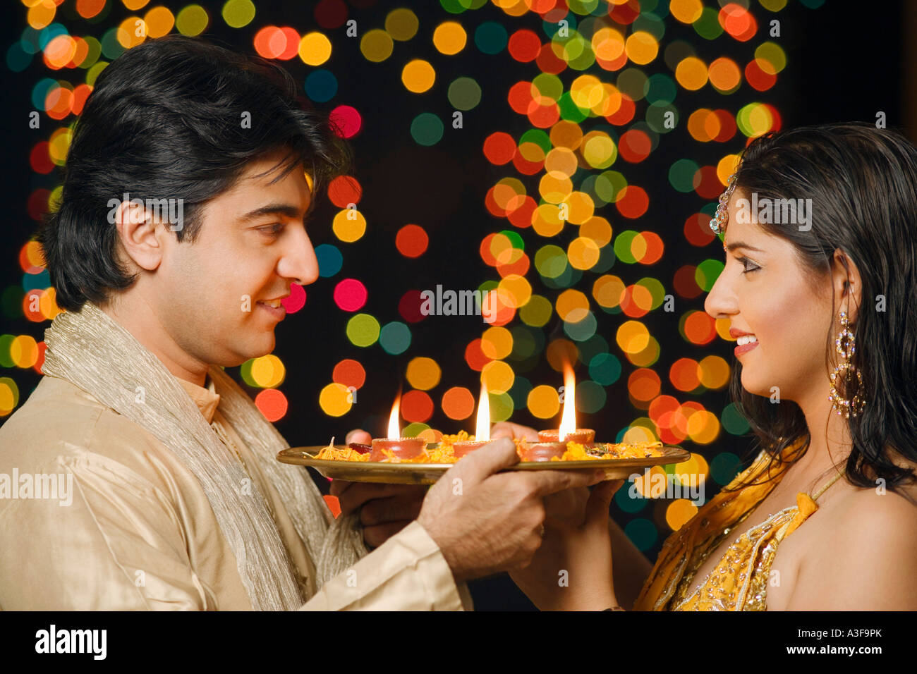Side profile of a young couple holding a plate of religious offerings ...