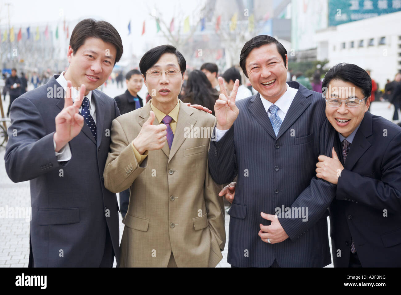 Portrait of four businessmen making hand signs Stock Photo - Alamy