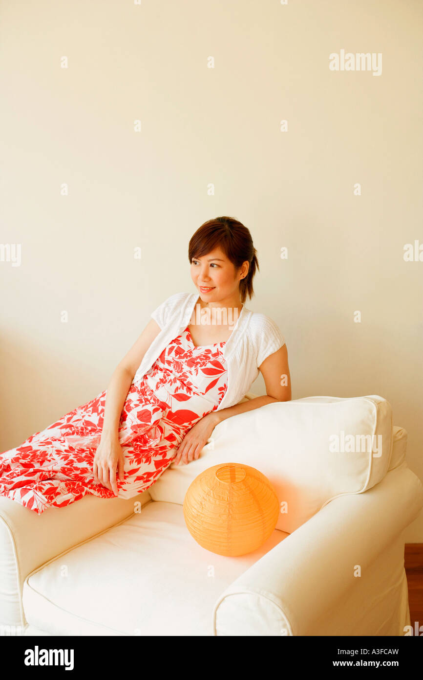 Young woman leaning on a couch Stock Photo - Alamy