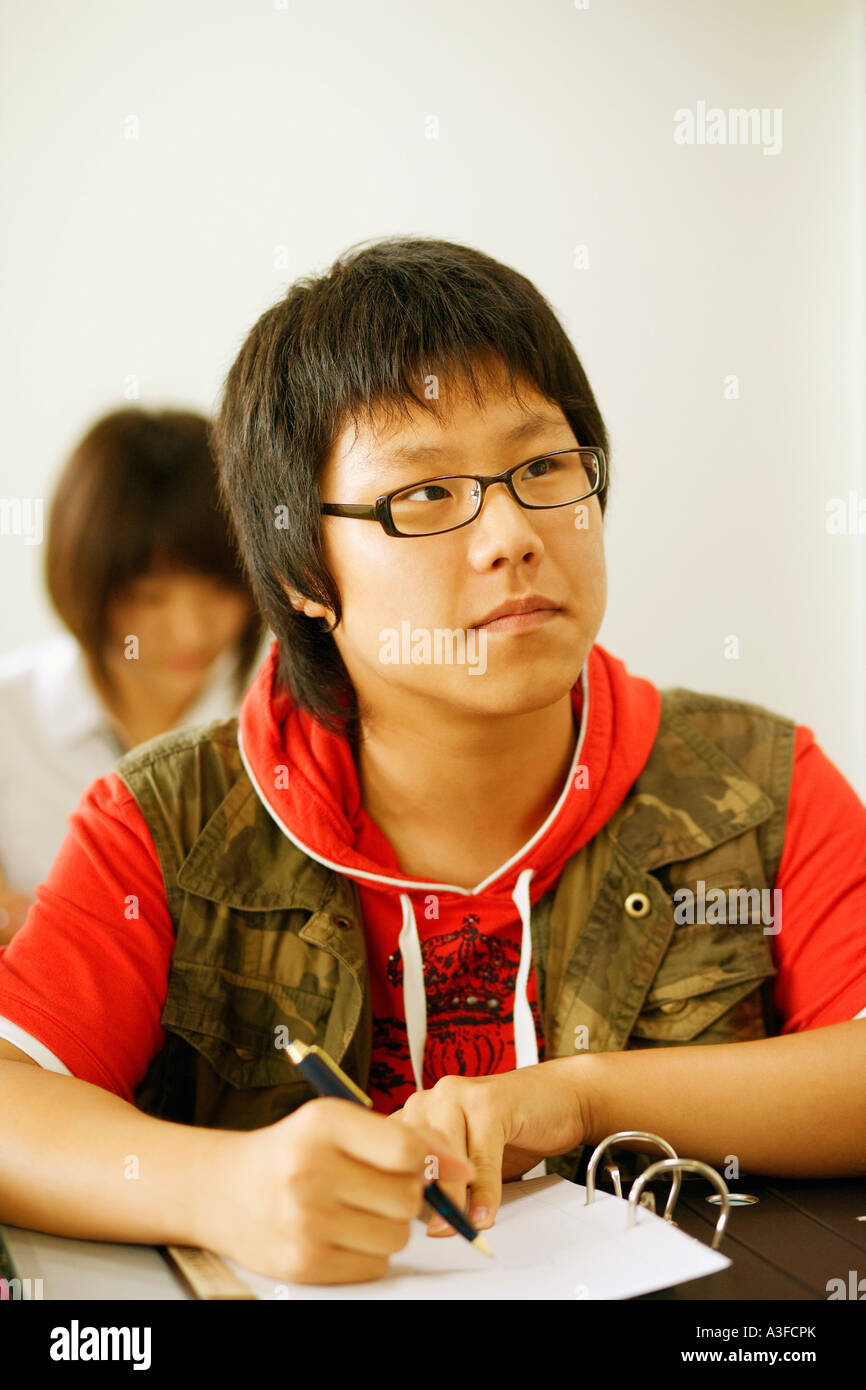 Close-up of a teenage boy holding a pen on a spiral notebook Stock ...