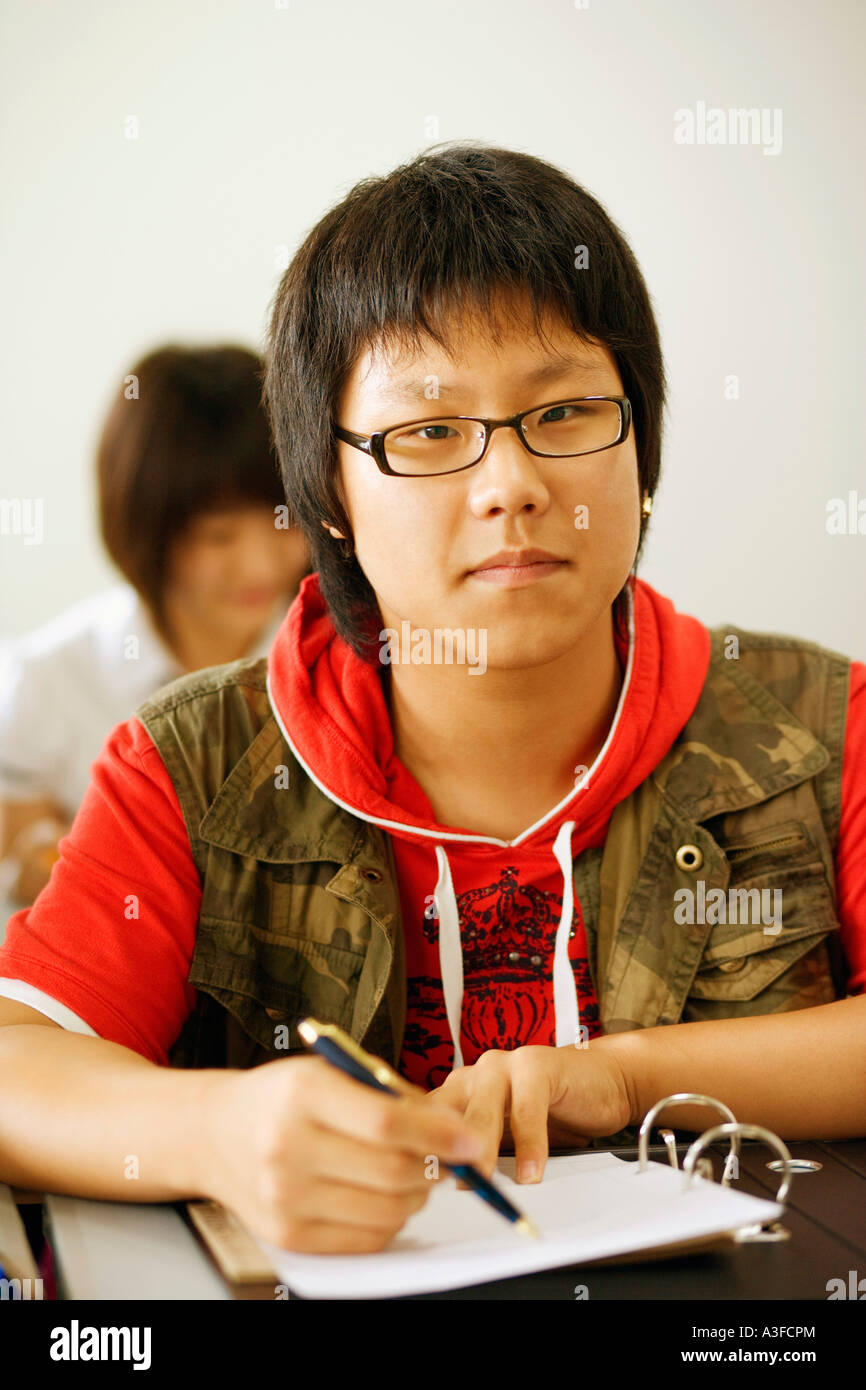Portrait of a teenage boy holding a pen on a spiral notebook Stock ...