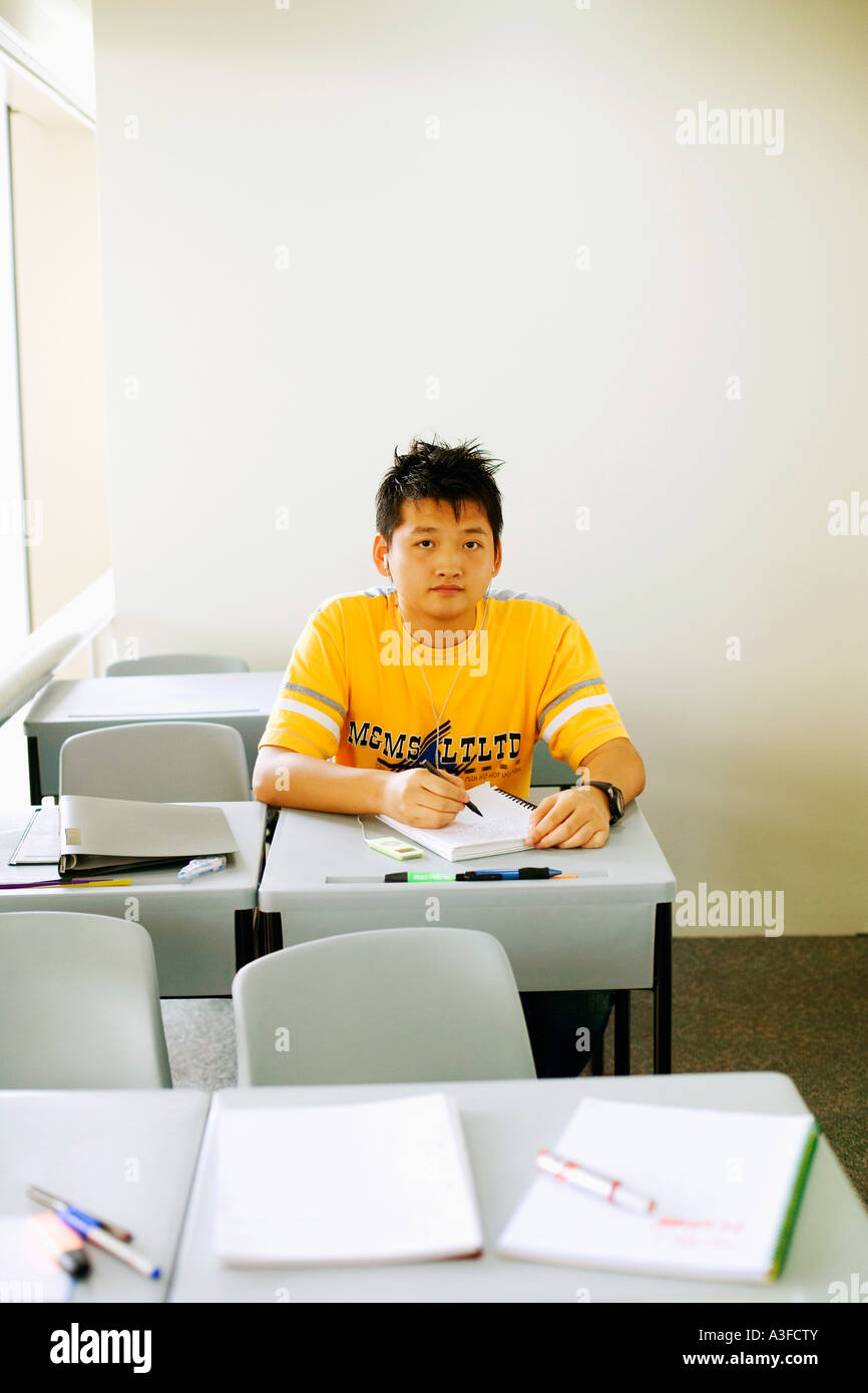 Portrait of a young man writing on a notepad in the classroom Stock ...
