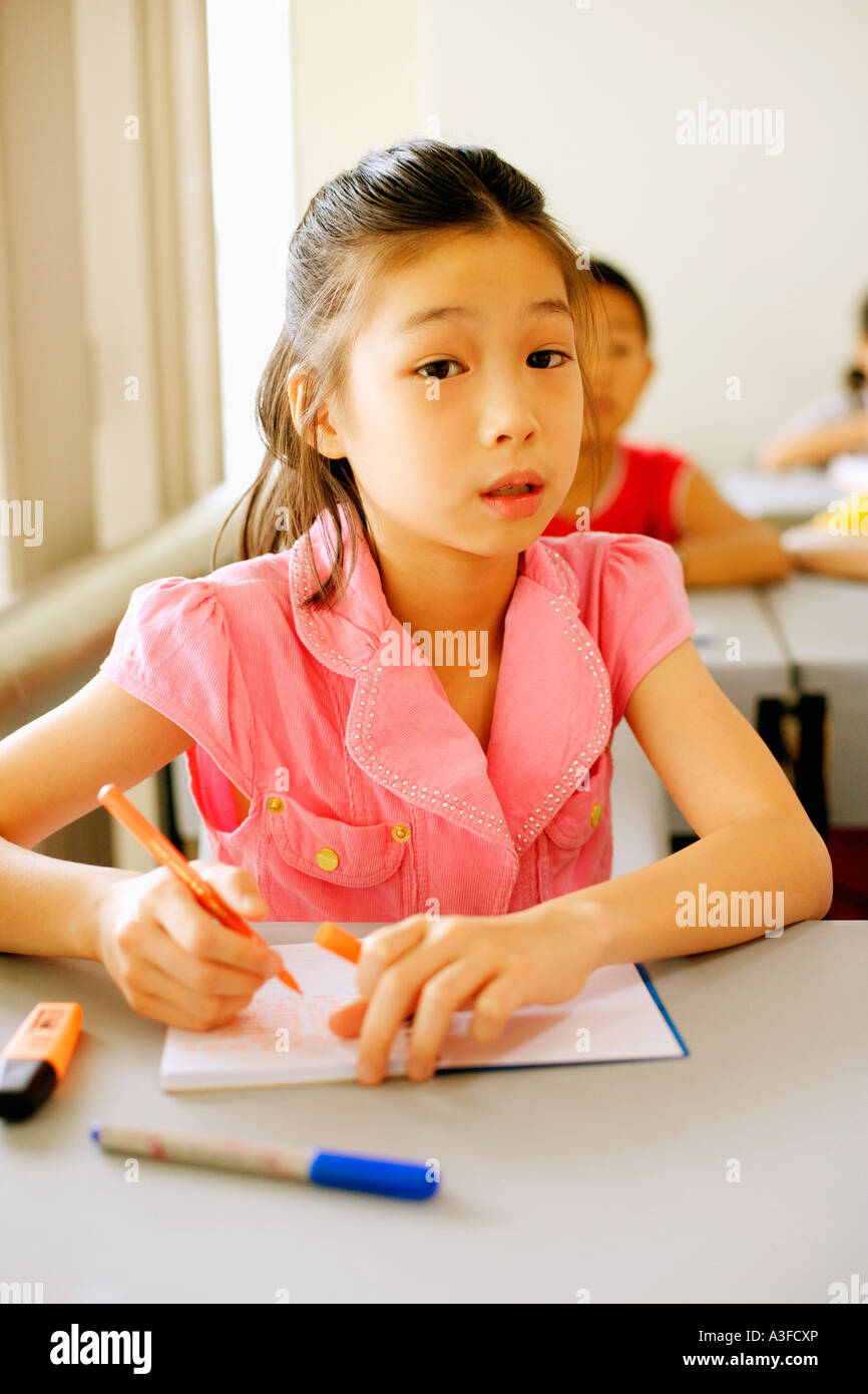 Portrait of a girl writing in a spiral notebook in the classroom Stock ...
