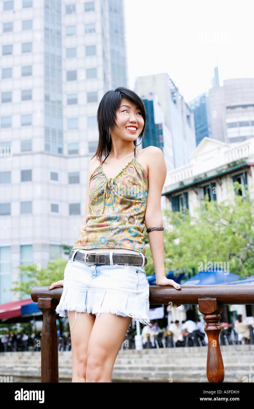 Young woman leaning against a railing Stock Photo - Alamy