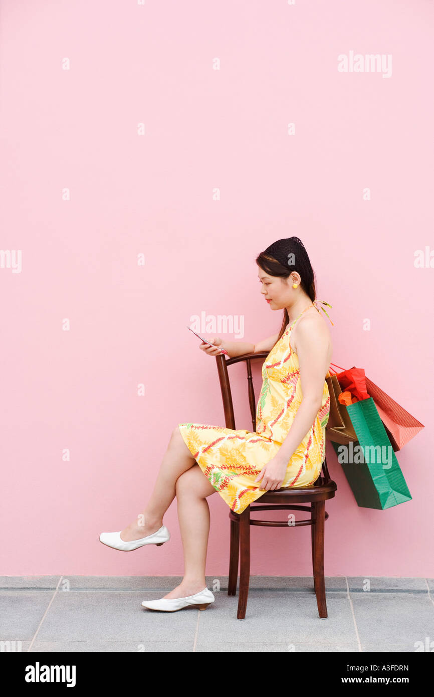 Side profile of a young woman sitting on a chair and using a mobile ...