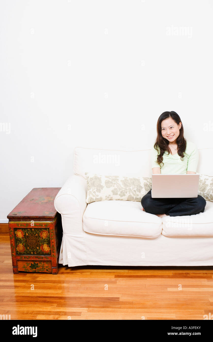 Young woman sitting on a couch and using a laptop Stock Photo - Alamy