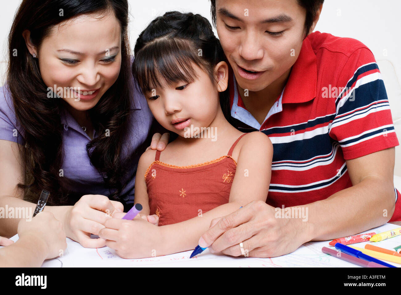 Close-up of parents drawing on paper with their daughter Stock Photo ...